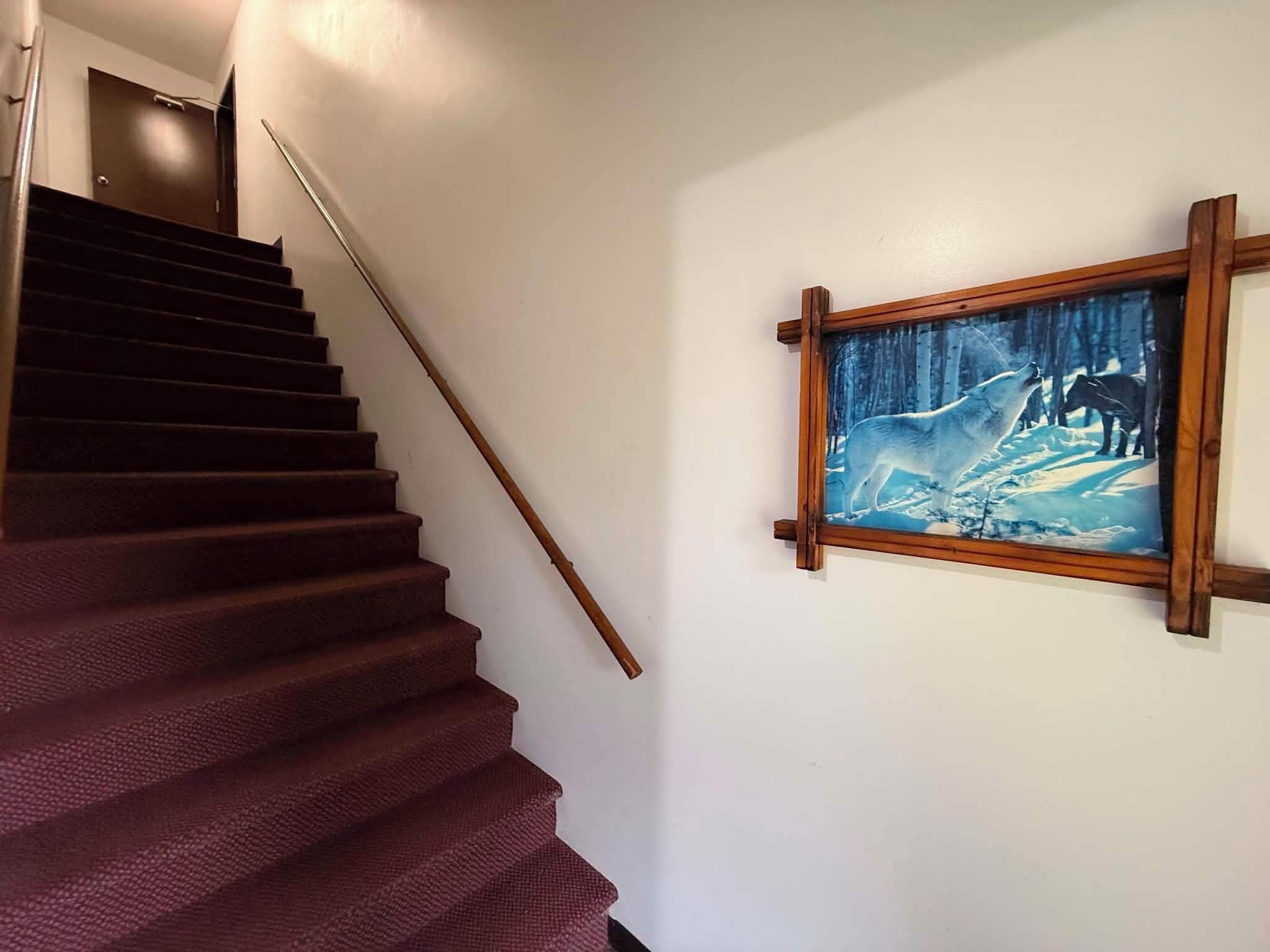 Uma escada com corrimão de madeira e um quadro de um lobo na parede.