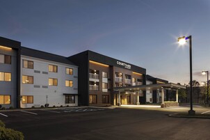 Um hotel Courtyard by Marriott com design moderno, várias varandas e uma entrada bem iluminada.