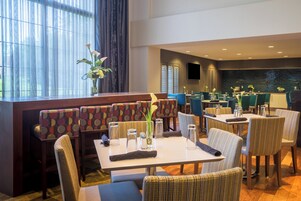 Um restaurante com cabines e mesas, algumas com centros de mesa florais.