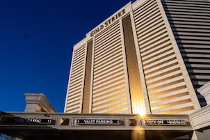 Um hotel com a sinalização "Gold Strike", placas indicando "Tráfego Contínuo" e "Estacionamento com Manobrista", e placas de "Entrega" e "Bagagem".
