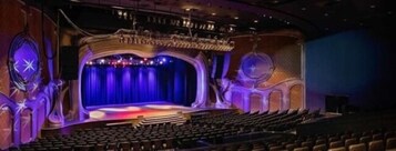 Um teatro com palco, assentos e um grande candelabro.