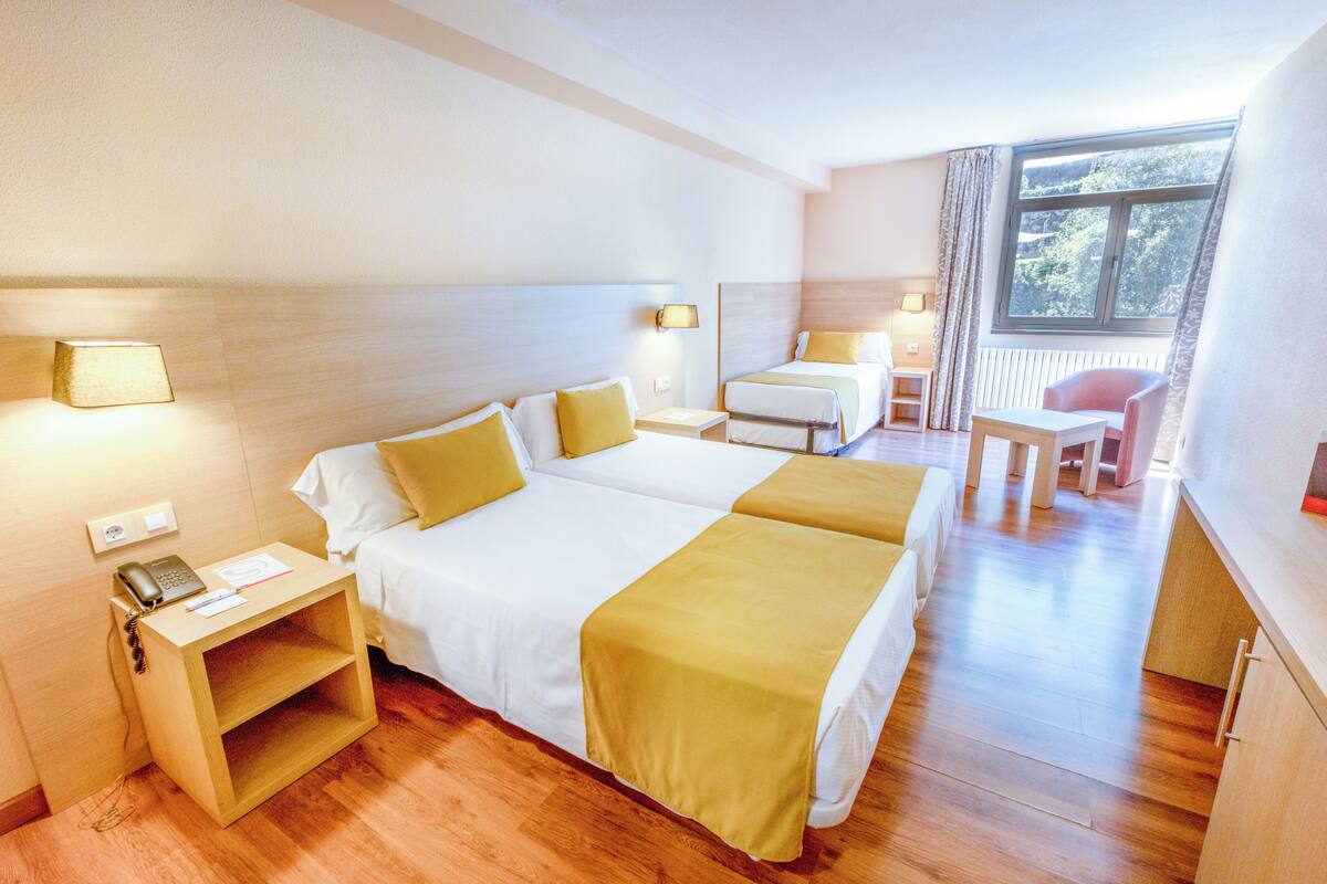 Quarto de hotel com cama grande, mesas de cabeceira, escrivaninha e uma cadeira.