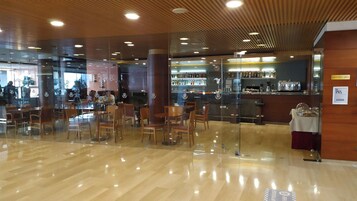 Um interior moderno com piso de madeira polida, divisórias de vidro e um espaço bar com diversos frascos.