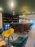 Uma área de bar com balcão, banquetes e prateleiras cheias de garrafas e copos.