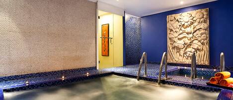 Uma piscina spa com parede texturizada, um painel decorativo e uma toalha na borda.