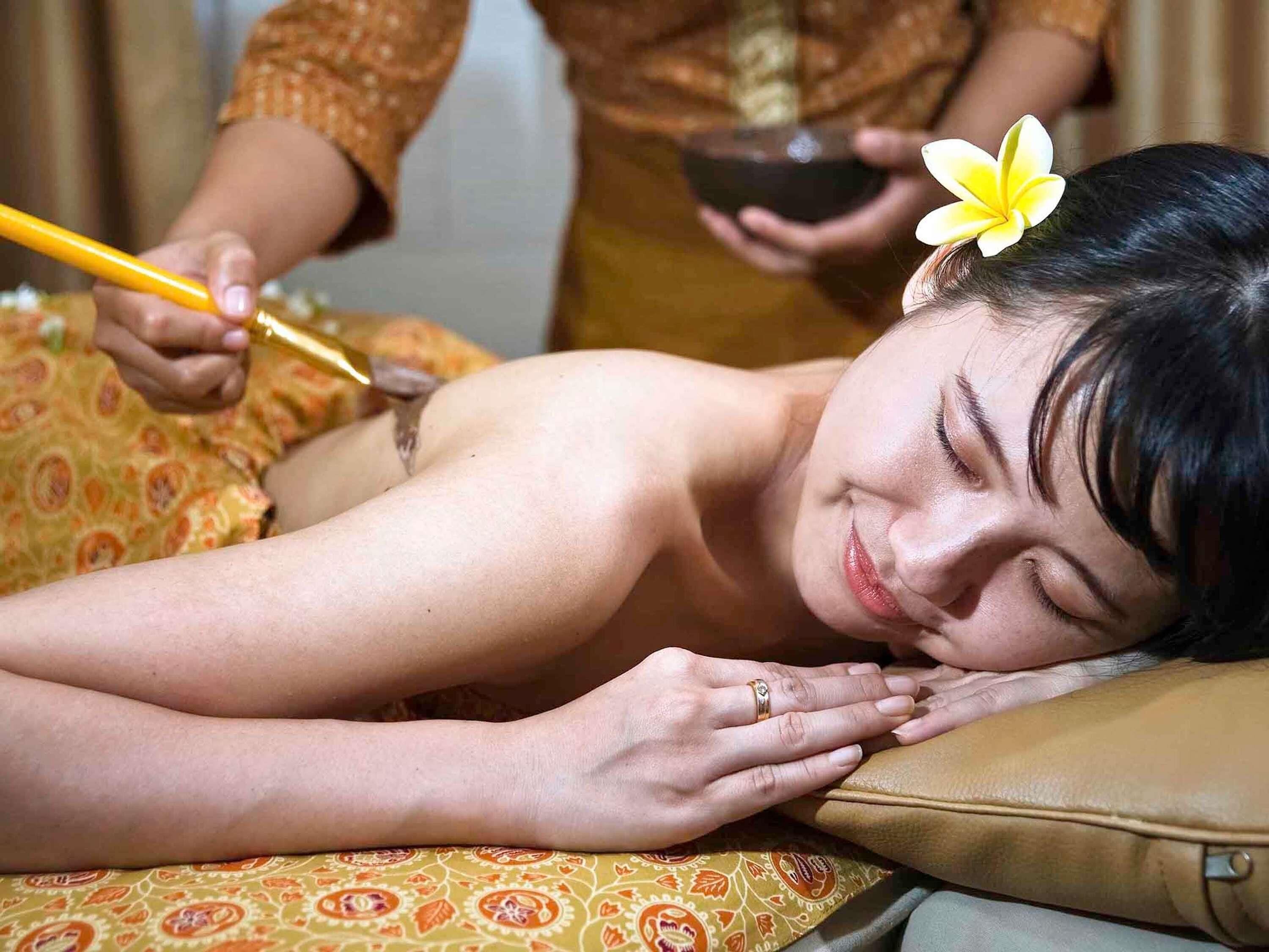 Uma pessoa recebendo massagem com uma flor no cabelo.