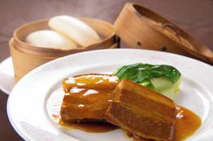 Um prato com carne glaceada e legumes, um cesto de madeira com ovos e um cozedor de bambu.