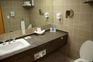 Casa de banho com lavatório, espelho, porta-toalhas e secador de cabelo.