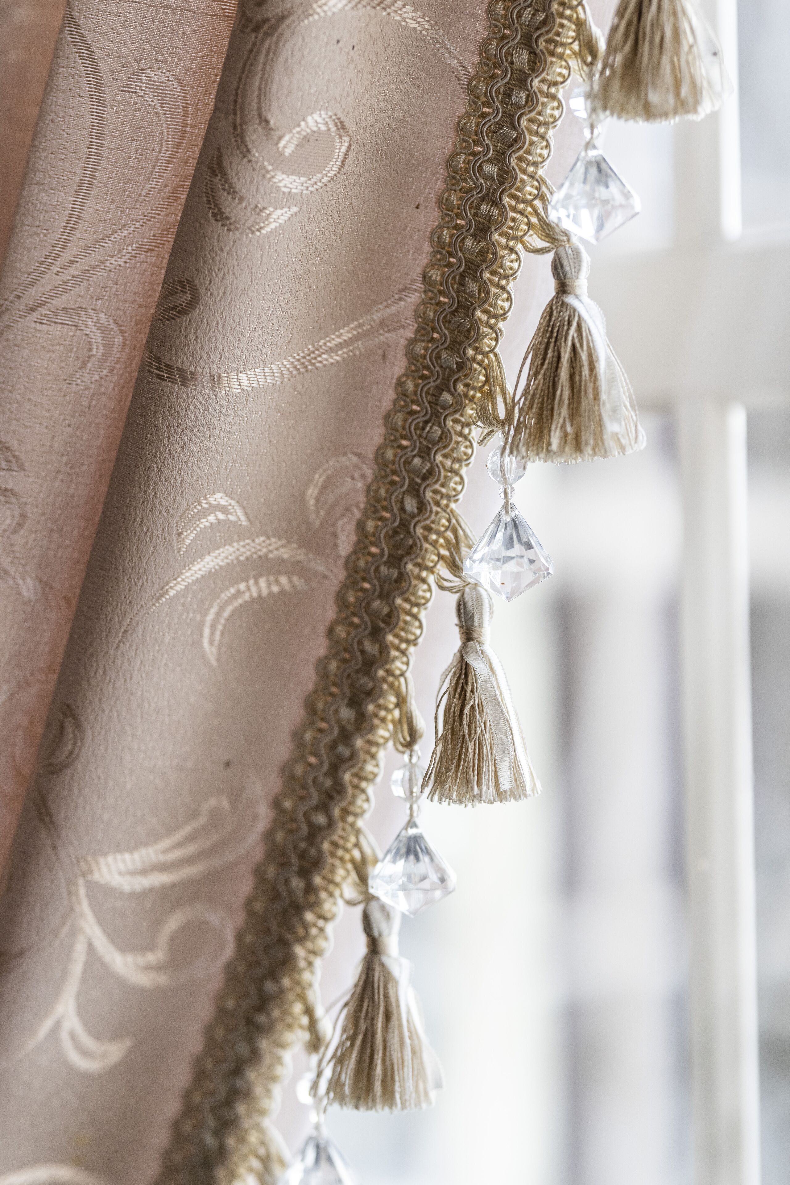 Close-up de cortina com franjas e detalhes de contas decorativas.