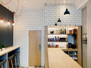 Cozinha moderna com paredes de tijolos brancos, balcão de madeira e luminárias pendentes.