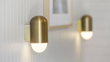 Duas luminárias de parede com acabamento em latão e lâmpadas brancas.