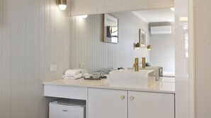 Casa de banho moderna com toucador branco, espelho grande e lavatório embutido.