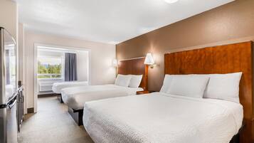 Quarto de hotel com duas camas, uma janela grande com vista e cabeceira de madeira.