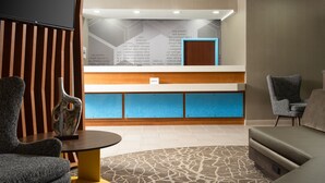Uma área de recepção com design moderno, incluindo um balcão de atendimento, espaço de estar com sofás e um tapete estampado.