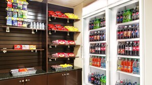 Exposição de lanches e bebidas em uma loja, com diversas opções em prateleiras.
