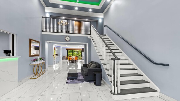 Um lobby moderno de hotel, com escadaria, balcão de recepção e área de estar.