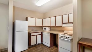 Cozinha compacta com eletrodomésticos brancos, armários de madeira e um padrão de piso em herringbone.