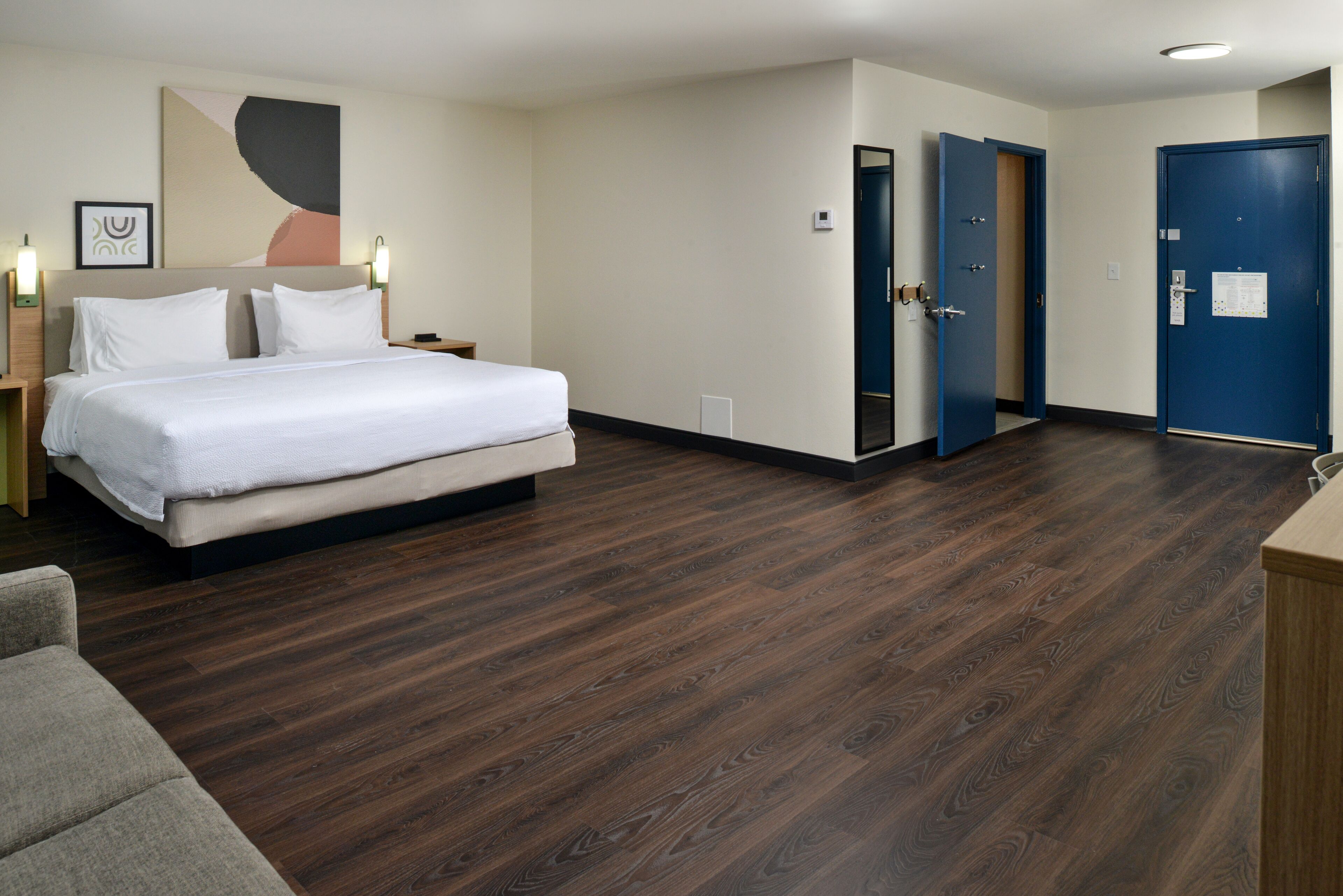 Quarto de hotel com uma cama grande, uma escrivaninha e um guarda-roupa.