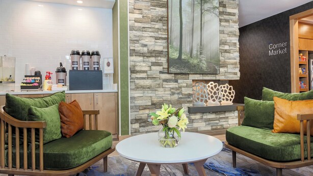 Um lobby moderno com parede de pedra, uma pintura de uma floresta e um espaço para café.