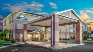 Um hotel Days Inn com entrada coberta, pilares de tijolo e estacionamento.