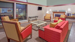 Sala de estar com sofá vermelho, cadeiras estampadas, mesa de centro de vidro e lareira.