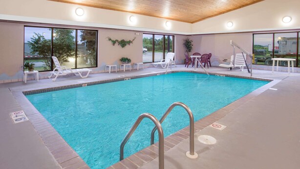 Piscina interna com água azul cristalina, cercada por espreguiçadeiras e uma mesa.