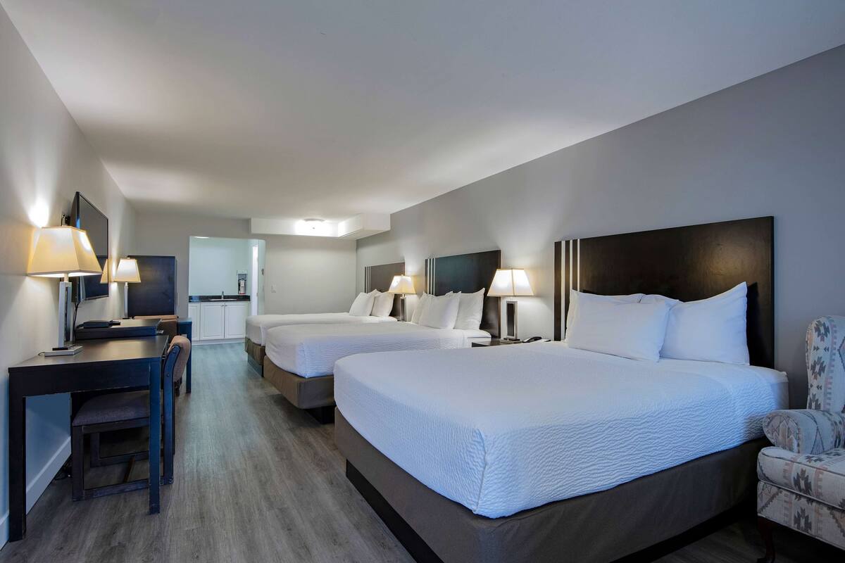 Quarto de hotel com duas camas, uma escrivaninha e uma cadeira.