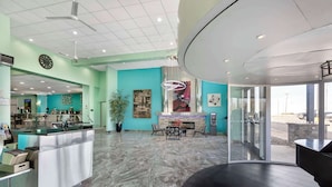 Um hall amplo com balcão de recepção, área de estar e uma grande janela com vista para o exterior.