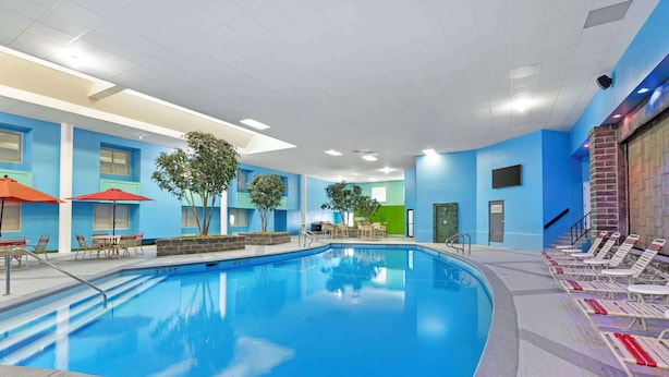 Uma piscina interior com água azul cristalina, rodeada por espreguiçadeiras e guarda-sóis.