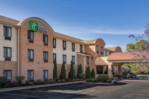Edifício Holiday Inn Express com fachada de tijolos, várias janelas e um estacionamento.