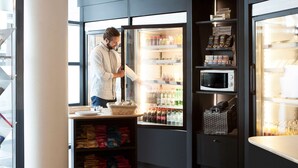 Uma cozinha moderna com geladeira, micro-ondas e bancada com alimentos.