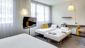 Quarto de hotel com duas camas, televisão, escrivaninha e abajur.