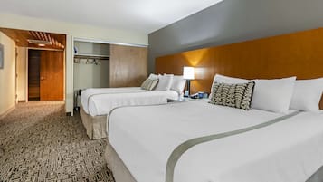 Quarto de hotel com duas camas, um closet espaçoso e um tapete estampado.