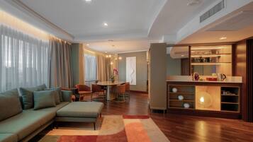 Uma sala de estar moderna com sofá, banqueta e uma área de jantar com mesa e cadeiras.