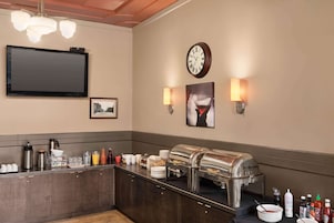 Uma área de pequeno-almoço de hotel com buffet, um relógio e obras de arte nas paredes.