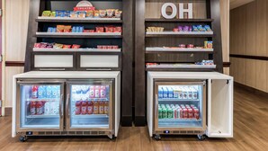 Exposição de petiscos e bebidas com dois refrigeradores, um com refrigerantes e outro com cerveja.
