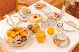 Uma mesa de café da manhã com croissants, frutas, suco e café.