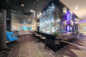 Uma área de bar moderna com um balcão comprido, banquetas e diversas garrafas.