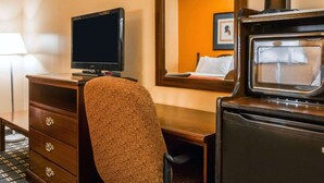 Quarto de hotel com televisão, máquina de café, secretária e uma cadeira.