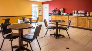 Uma área de refeições com mesas e cadeiras, um balcão de cozinha com eletrodomésticos e uma porta que dá para o exterior.