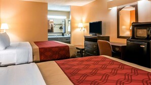 Quarto de hotel com duas camas, uma escrivaninha com computador, televisão e micro-ondas.