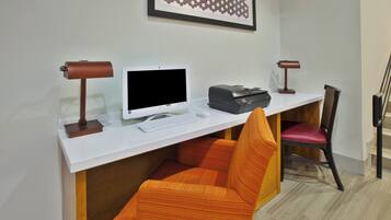 Um espaço de escritório em casa com escrivaninha, computador, impressora e cadeira.