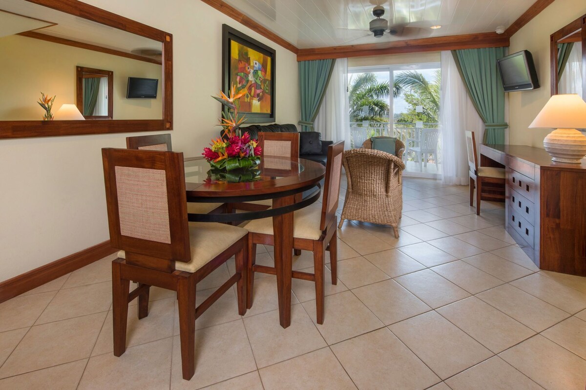Uma sala de jantar com uma mesa redonda, cadeiras, uma televisão e uma planta decorativa.