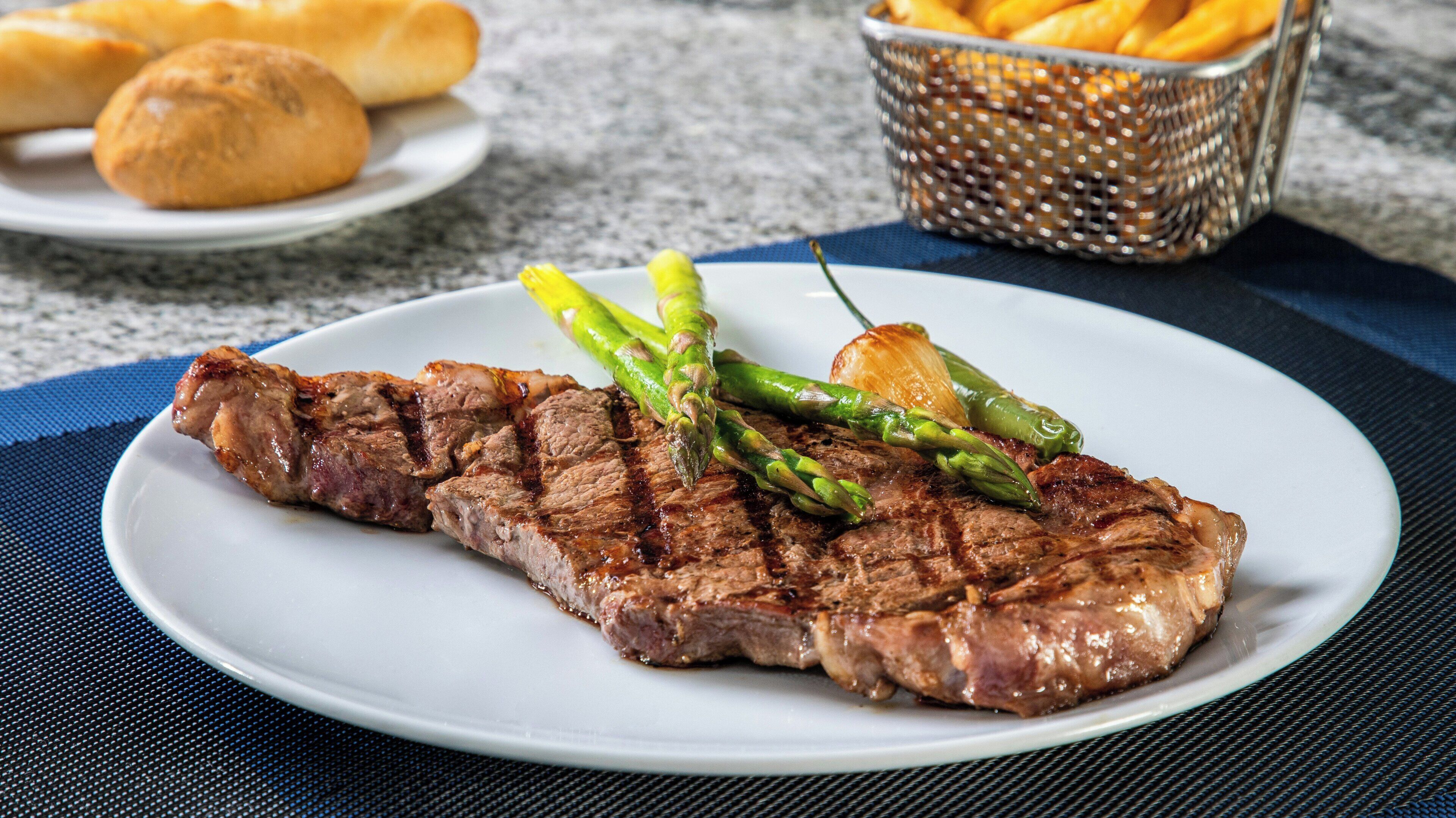 Prato com bife grelhado, aspargos e batatas assadas.