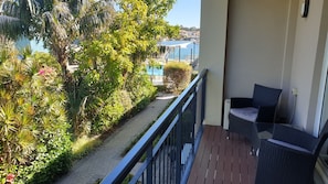 Uma varanda com vista para uma piscina, cercada por vegetação exuberante e um caminho pavimentado.