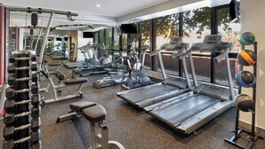 Uma academia com esteiras, aparelhos de musculação e diversos equipamentos de exercício.