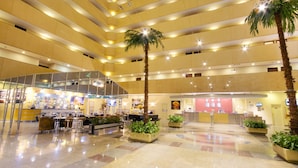 Um hall amplo com vários andares, um balcão de recepção e diversas áreas de estar.