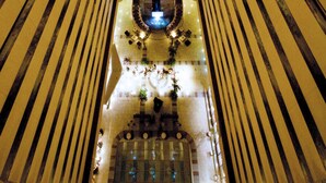 Um hotel com vários andares, um átrio central, várias varandas e piso refletivo.