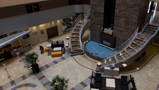 Um hall espaçoso com piscina central, diversas áreas de estar e uma escadaria curva.