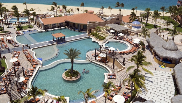 Resort com várias piscinas, áreas de descanso e vista para a praia.